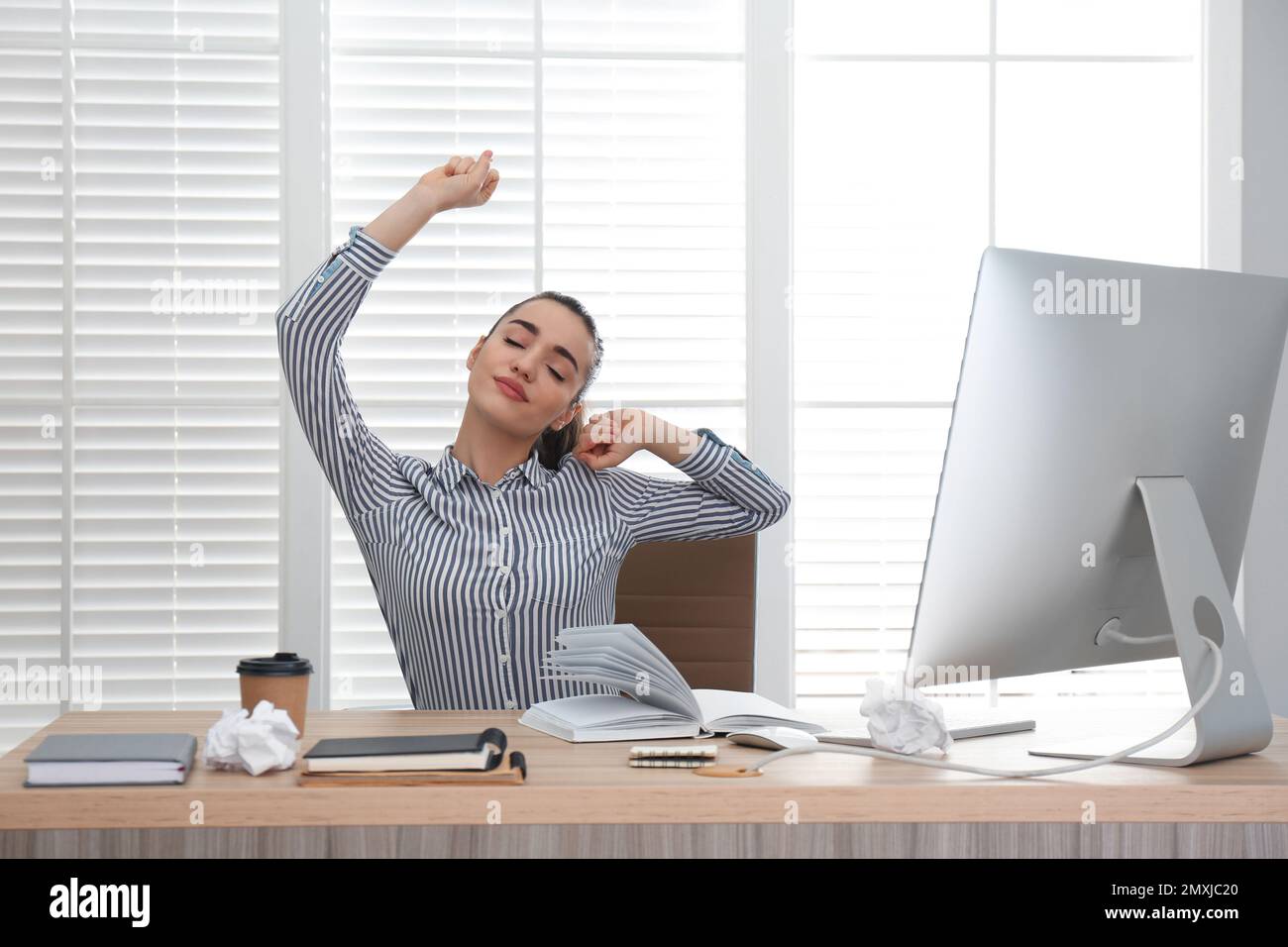 Lazy employee stretching at table in office Stock Photo - Alamy