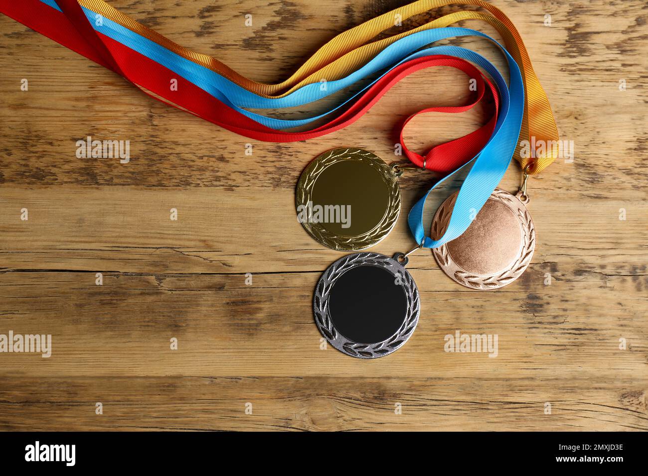 Gold, silver and bronze medals on wooden background, flat lay. Space ...