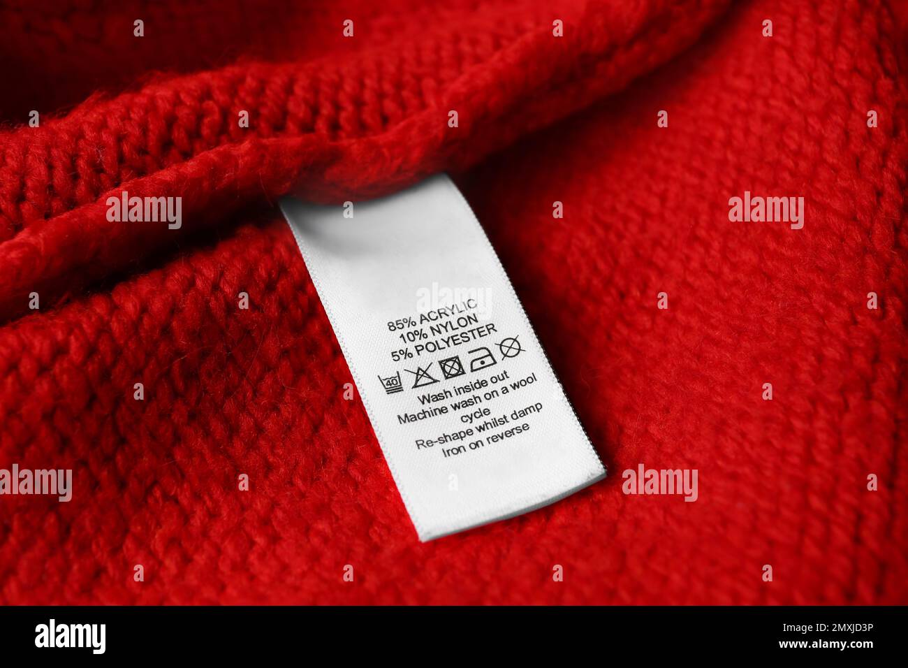 Clothing label with care symbols and material content on red sweater ...