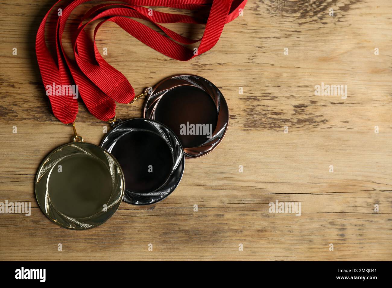 Gold, silver and bronze medals on wooden background, flat lay. Space ...