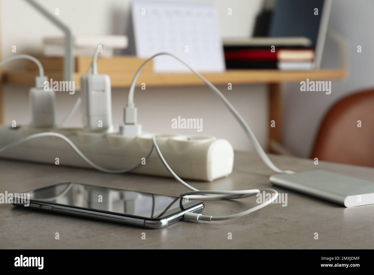 Devices charging with cable on light stone table Stock Photo - Alamy
