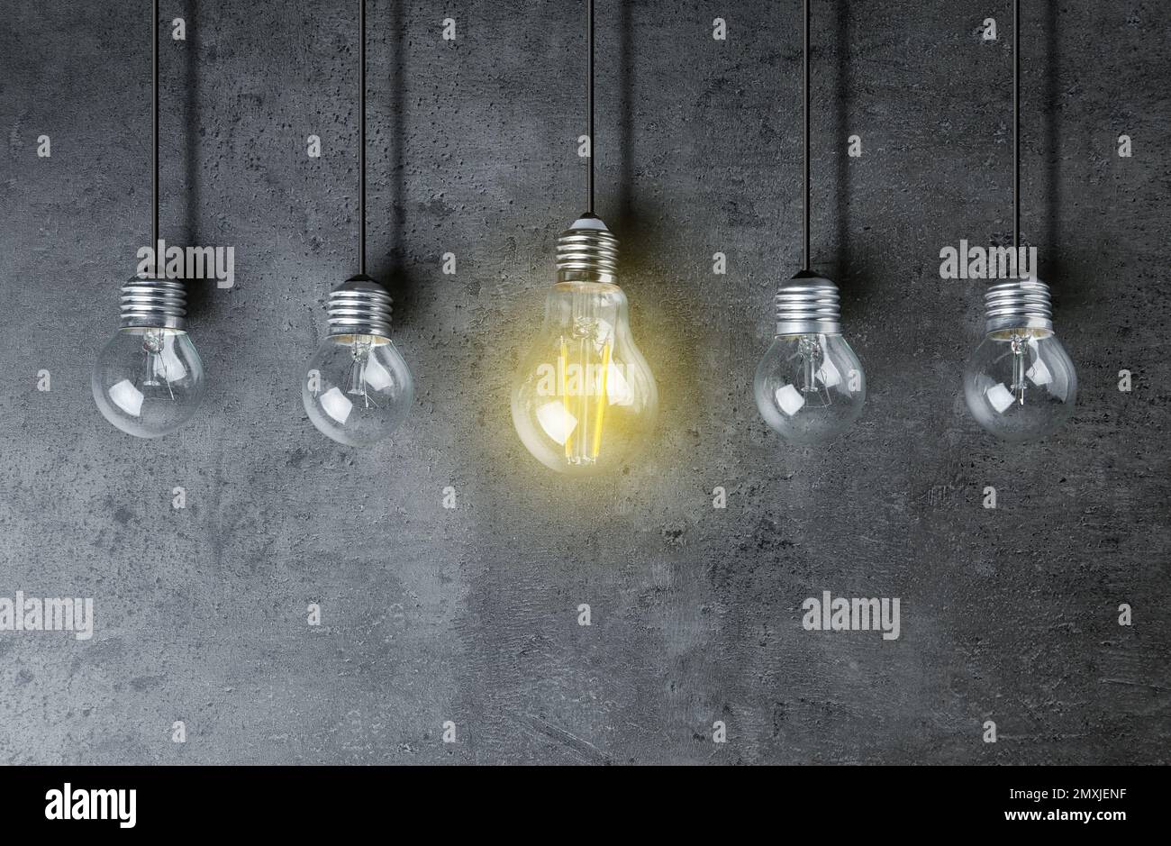 Idea concept. Glowing light bulb among others on grey background Stock ...