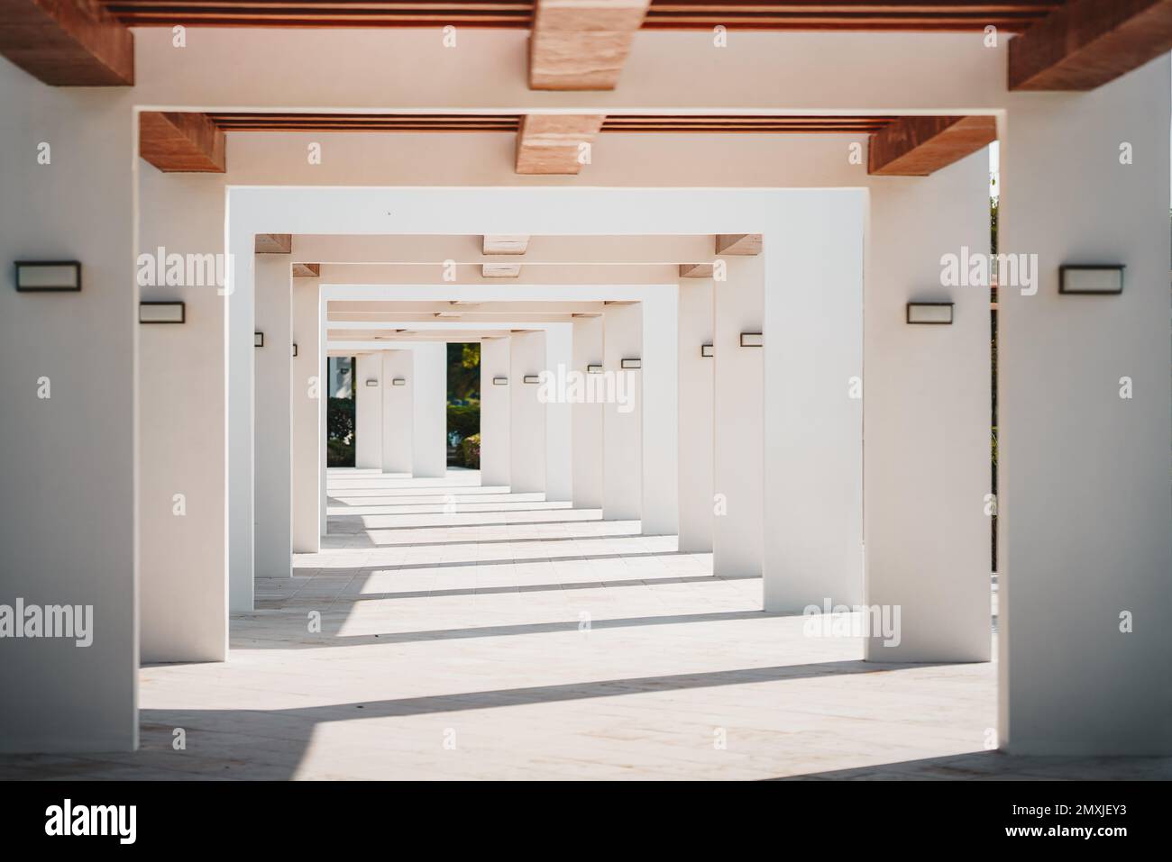 A long walkway leads to a bunch of white pillars with a wooden ceiling ...
