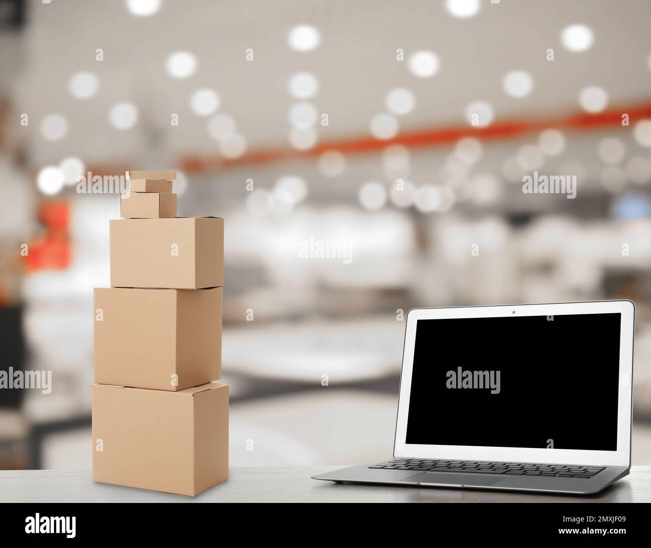 Online selling. Laptop and parcels on table in store Stock Photo - Alamy