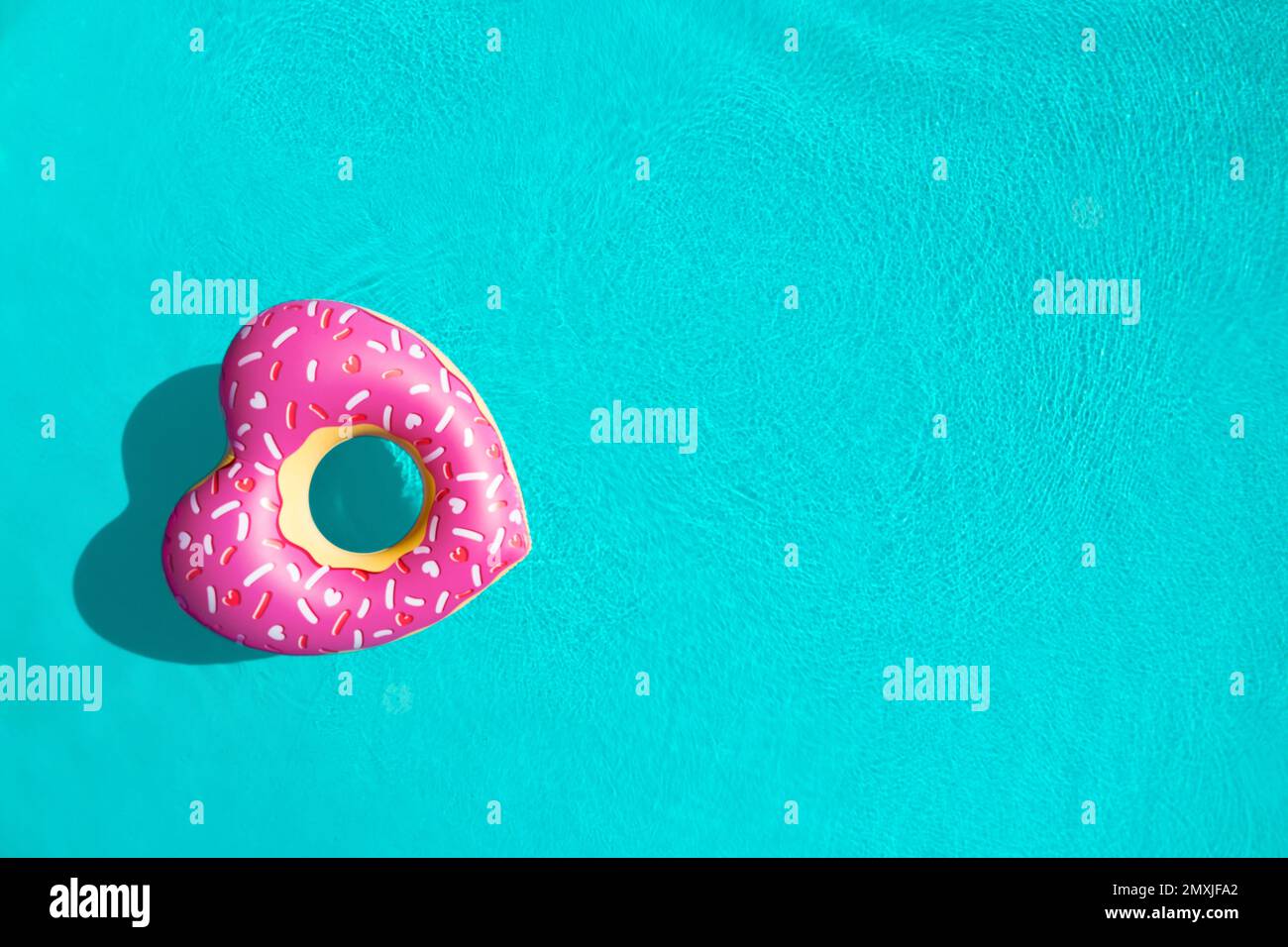 Heart shaped inflatable ring floating in swimming pool, top view with ...