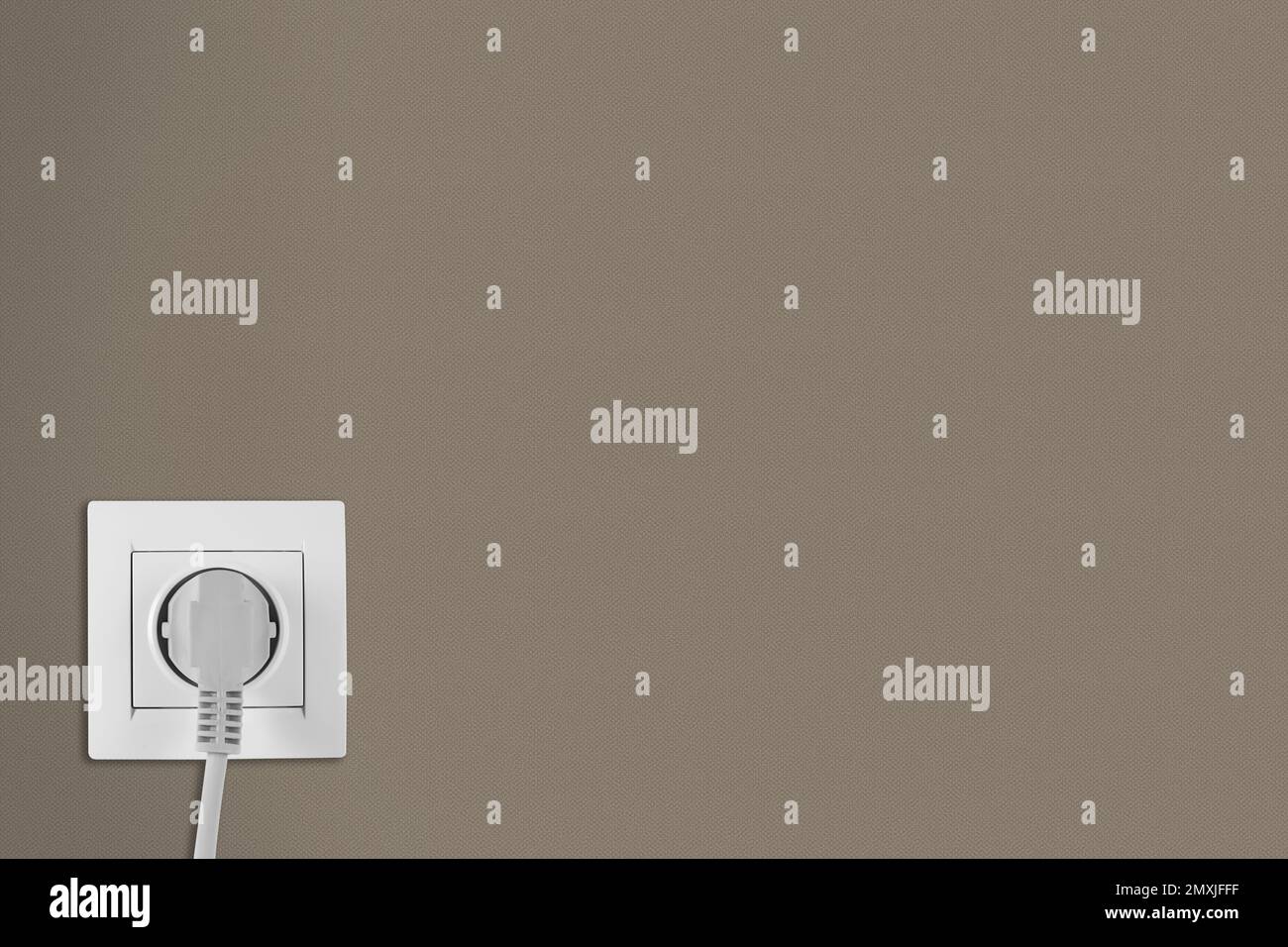 Brown wall with power socket and inserted plug, space for text ...