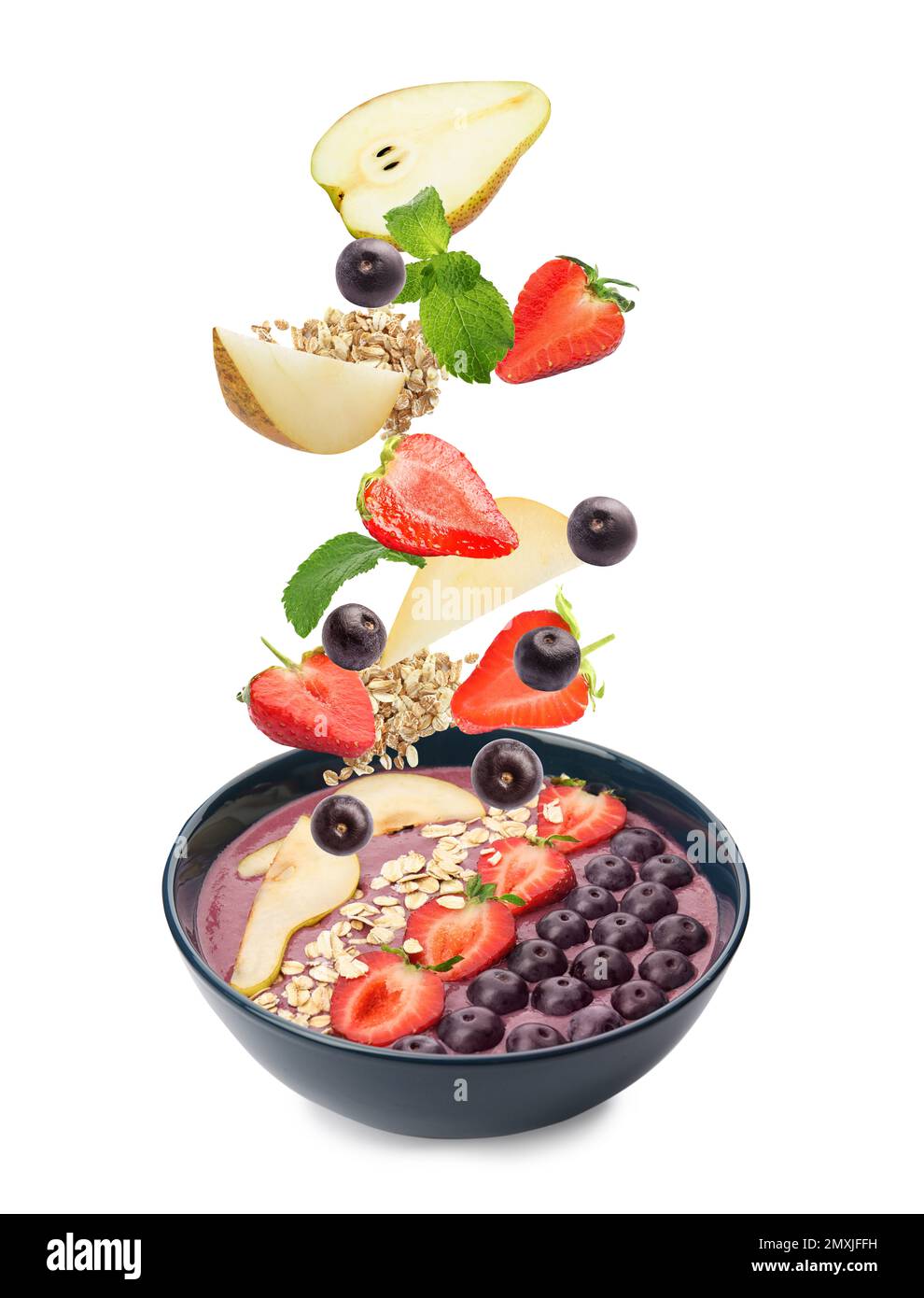 Acai berries and other ingredients falling into bowl on white ...