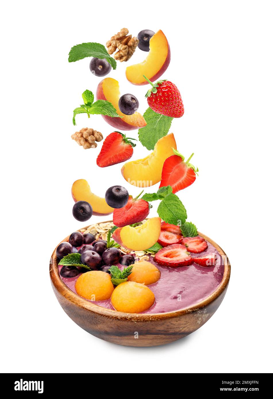 Acai berries and other ingredients falling into bowl on white ...