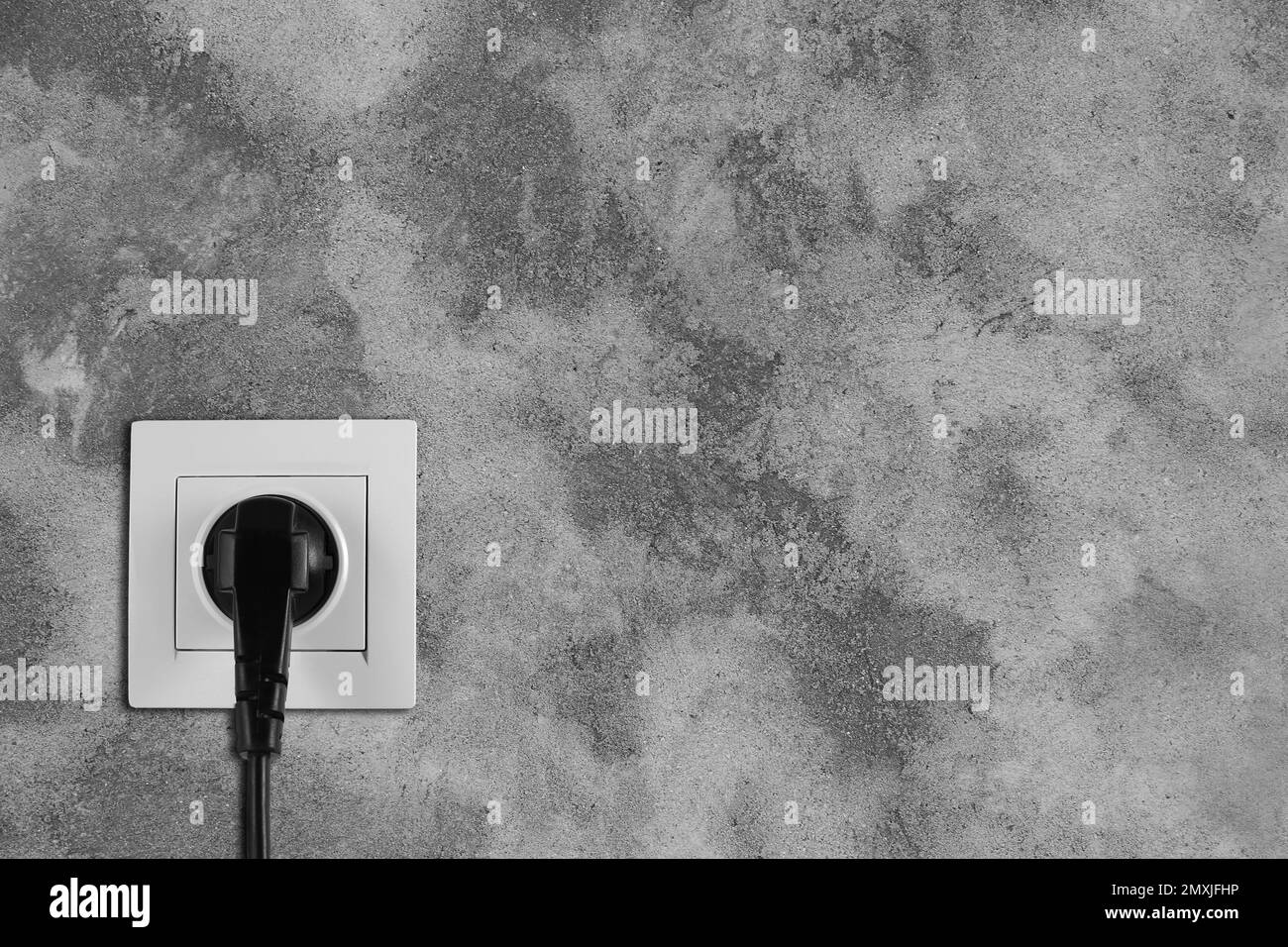 Stone wall with power socket and inserted plug, space for text ...