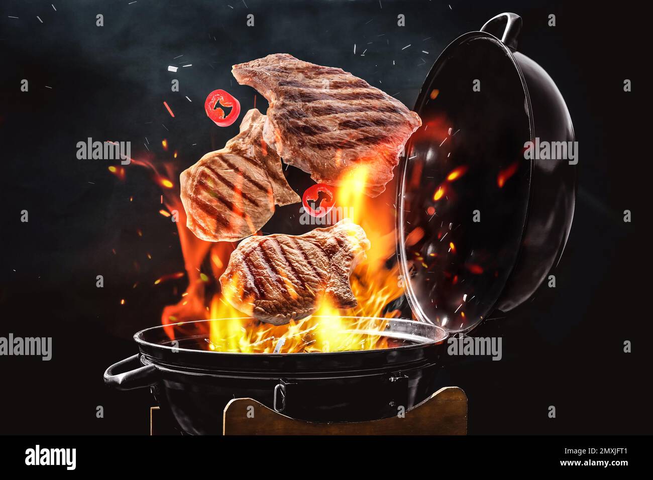 Meat and chili pepper slices falling onto barbecue grill with flame ...