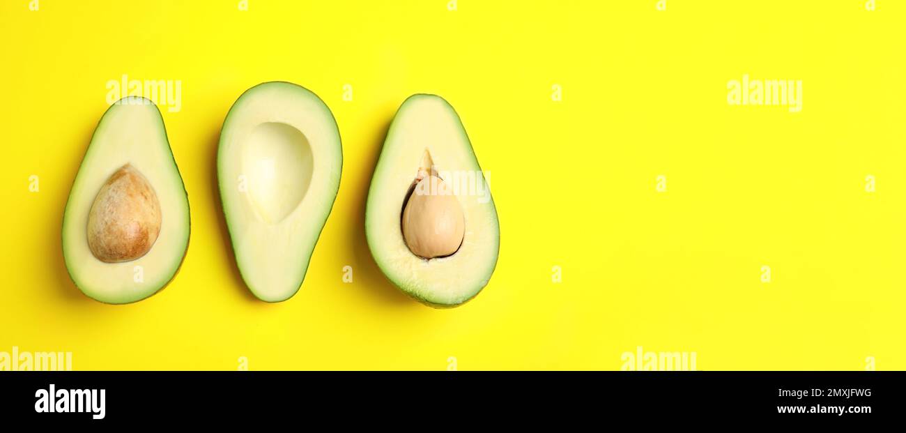 Cut fresh ripe avocados and space for text on yellow background, flat ...