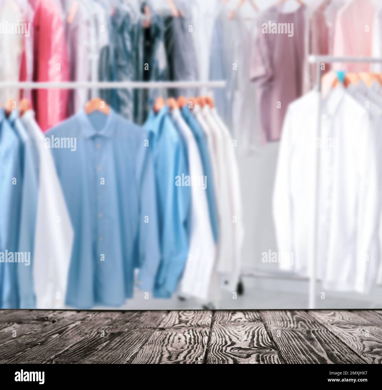 Empty black wooden surface and clean clothes on hangers in dry-cleaning ...