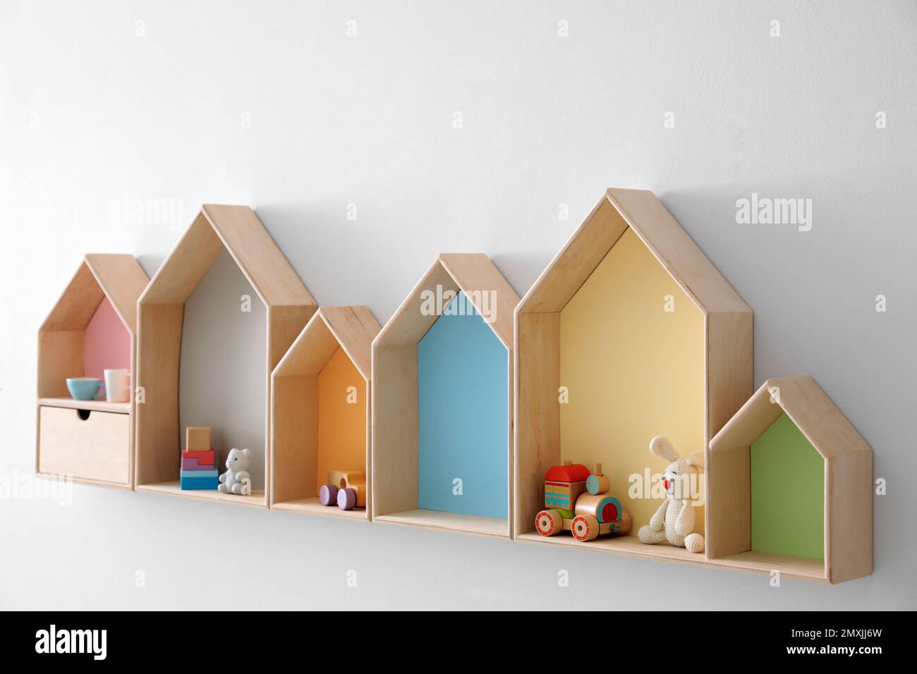 Different house shaped shelves with toys on white wall. Interior design ...