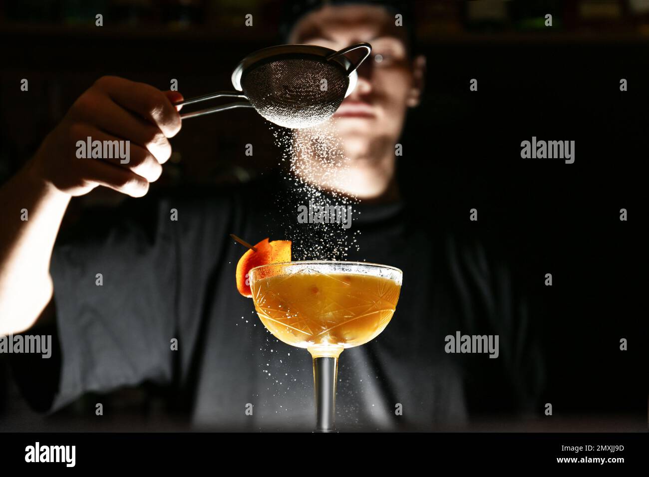 Bartender decorating fresh alcoholic cocktail in bar, focus on glass ...