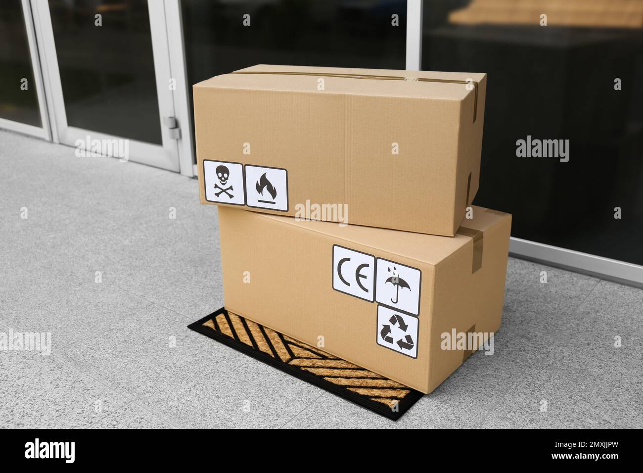 Cardboard boxes with different packaging symbols on door mat near ...