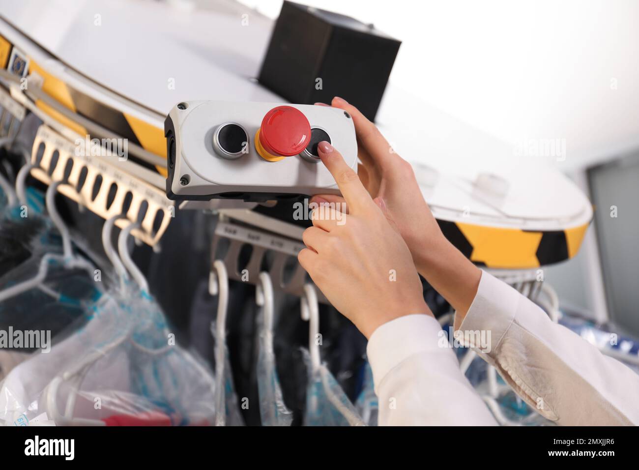 Worker pressing button on control panel of garment conveyor at modern ...