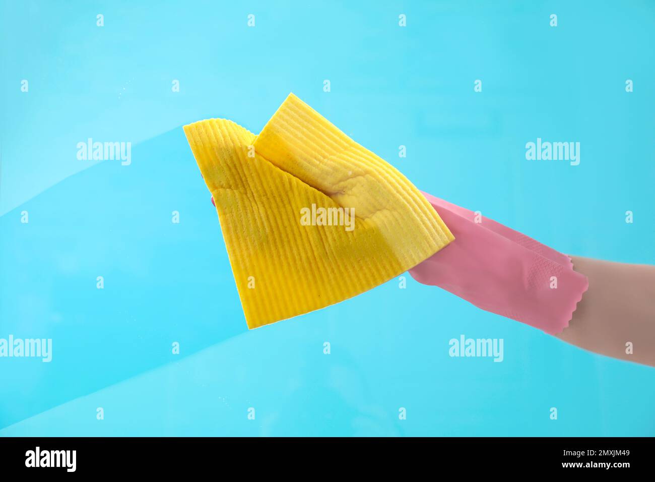 Young woman wiping glass with rag against color background. Cleaning ...