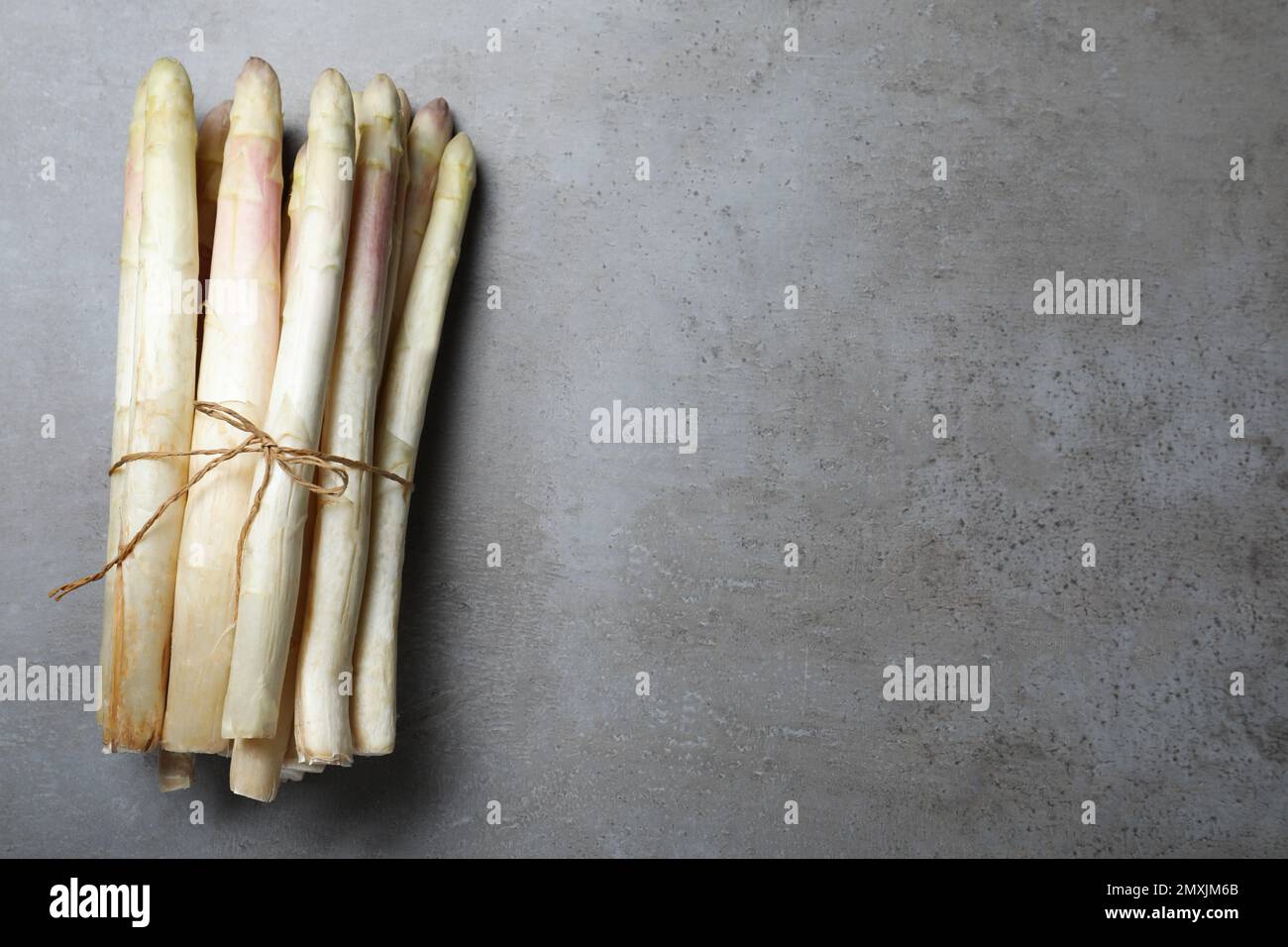 Bunch of fresh white asparagus on grey table, top view. Space for text ...