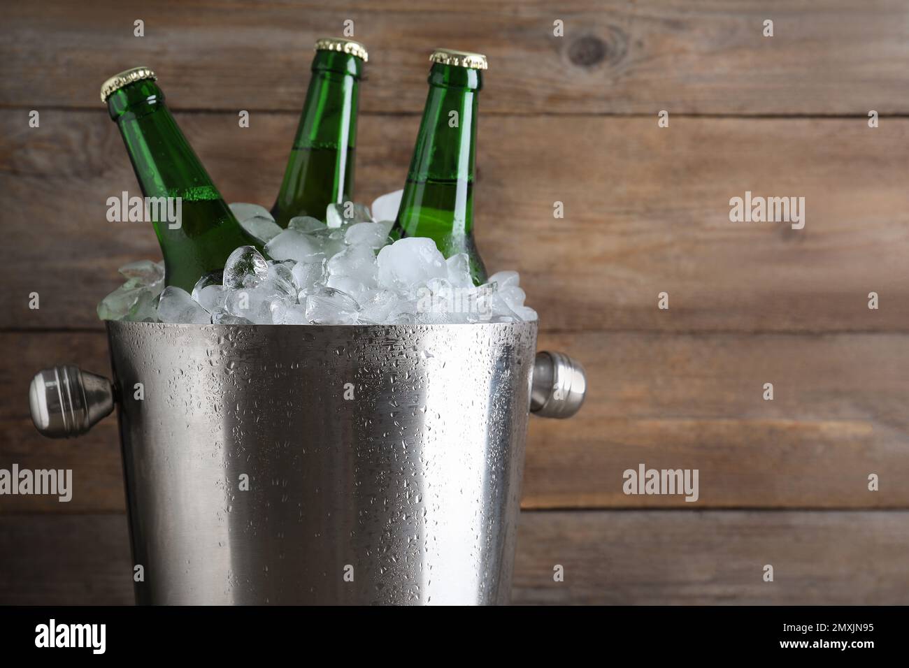 Metal bucket with beer and ice cubes on wooden background, closeup ...