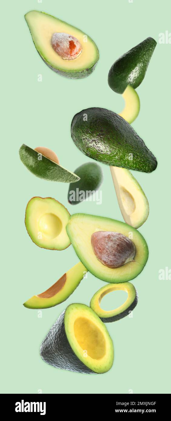Fresh ripe avocados falling on light blue background Stock Photo - Alamy
