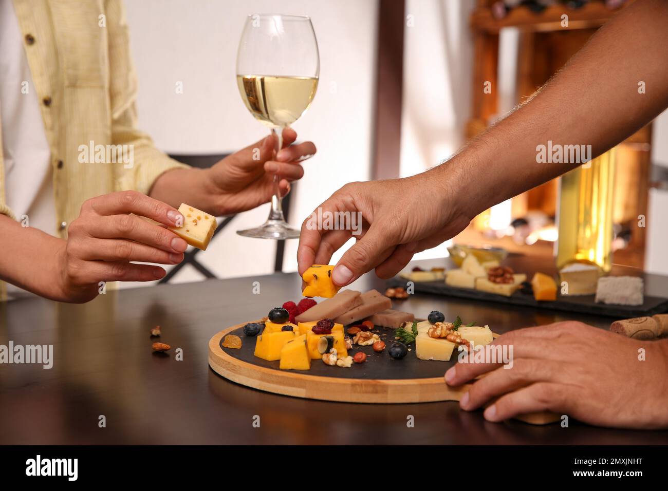 Couple with different types of delicious cheeses at table indoors ...