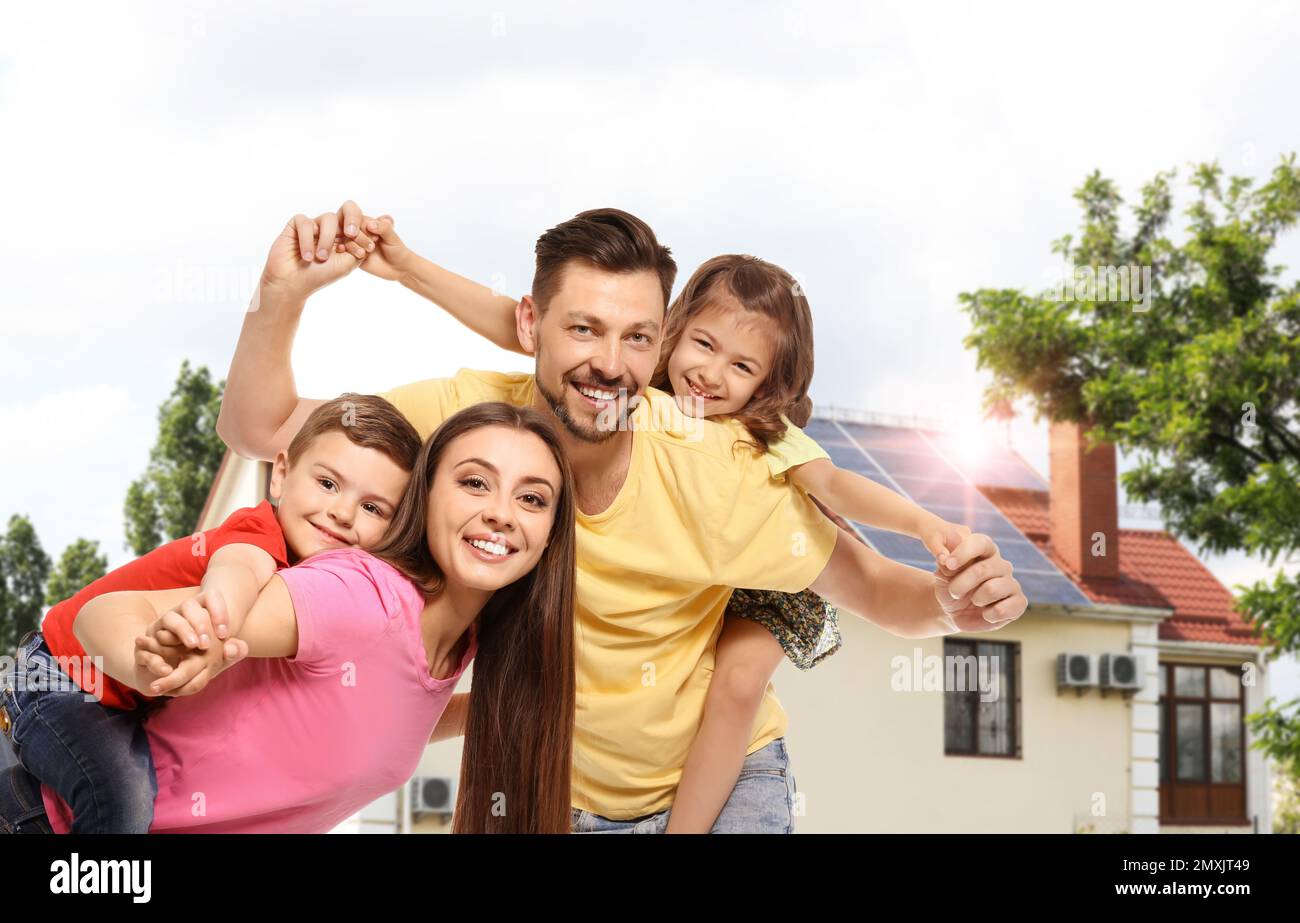 Happy family near their house with solar panels. Alternative energy ...