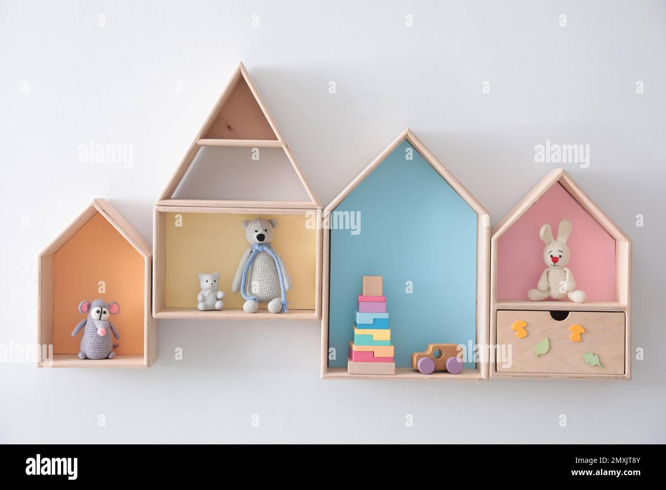 Different house shaped shelves with toys on white wall. Interior design ...