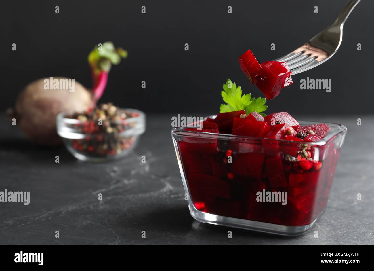 Pickled beets and fork over glass bowl on dark marble table Stock Photo ...