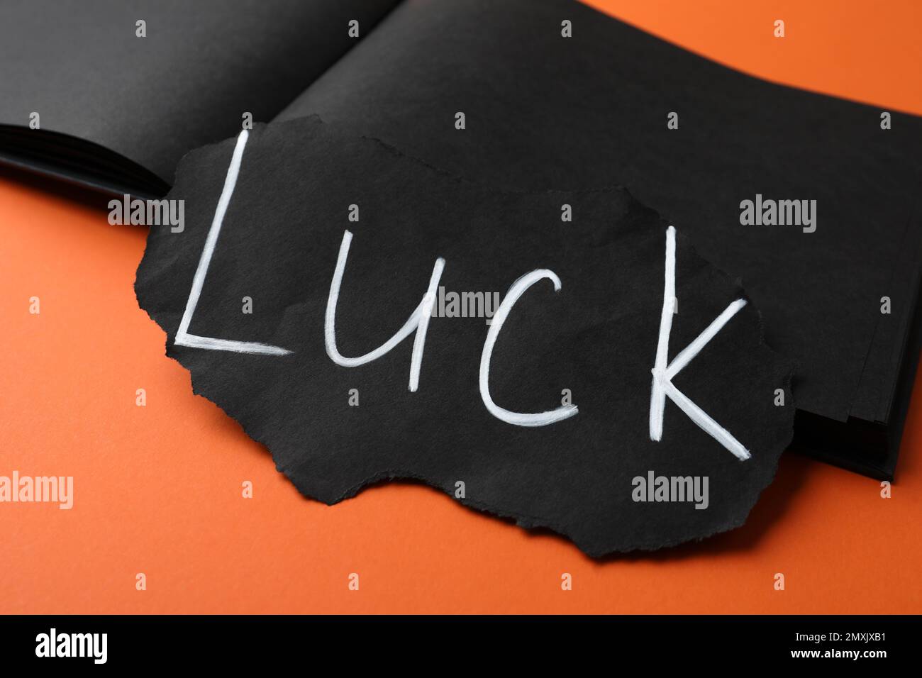 Sheet of paper and notebook with word LUCK on orange background ...