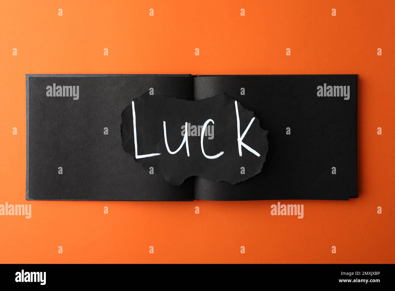 Sheet of paper with word LUCK and notebook on orange background, top ...