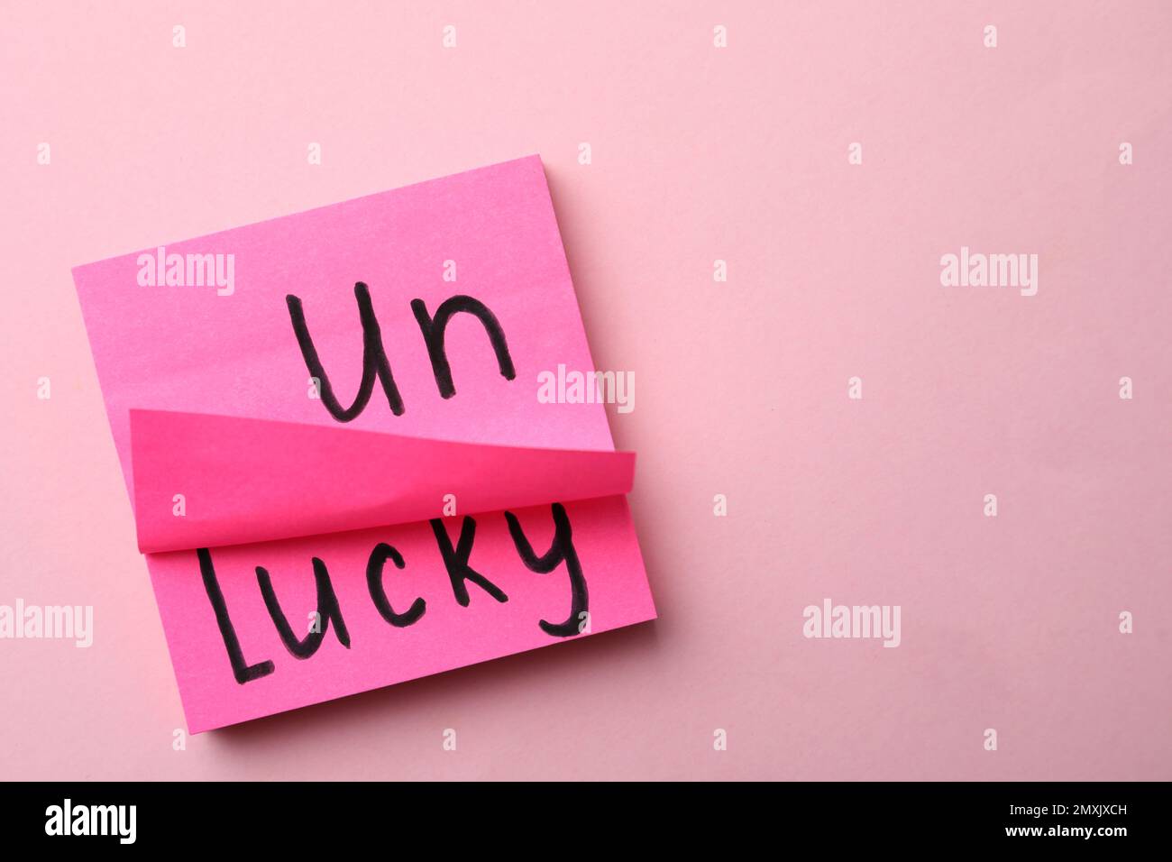 Notes with word UNLUCKY on pink background, top view. Space for text ...
