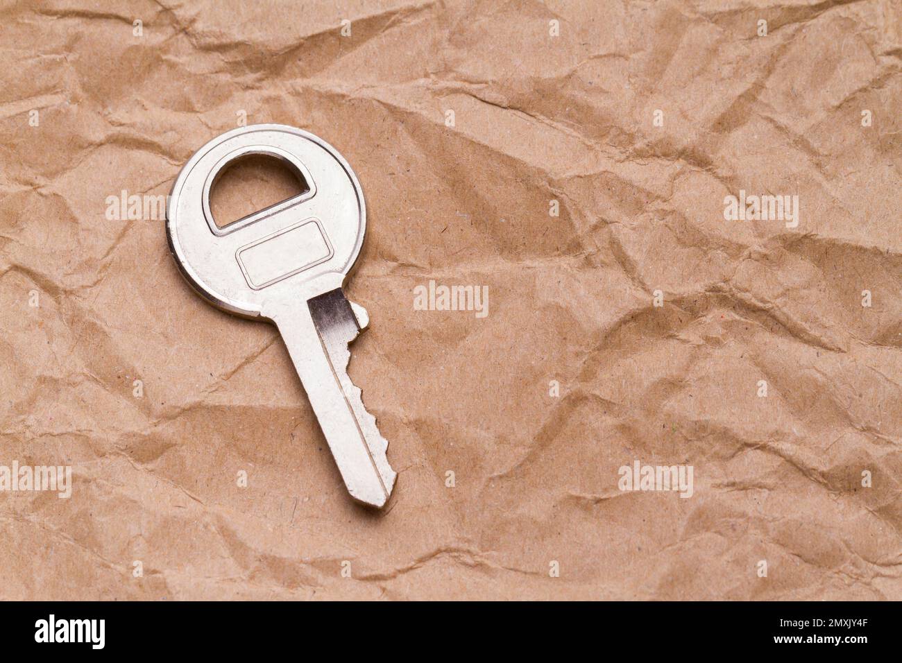 small steel key on crumpled paper background, space for text Stock ...