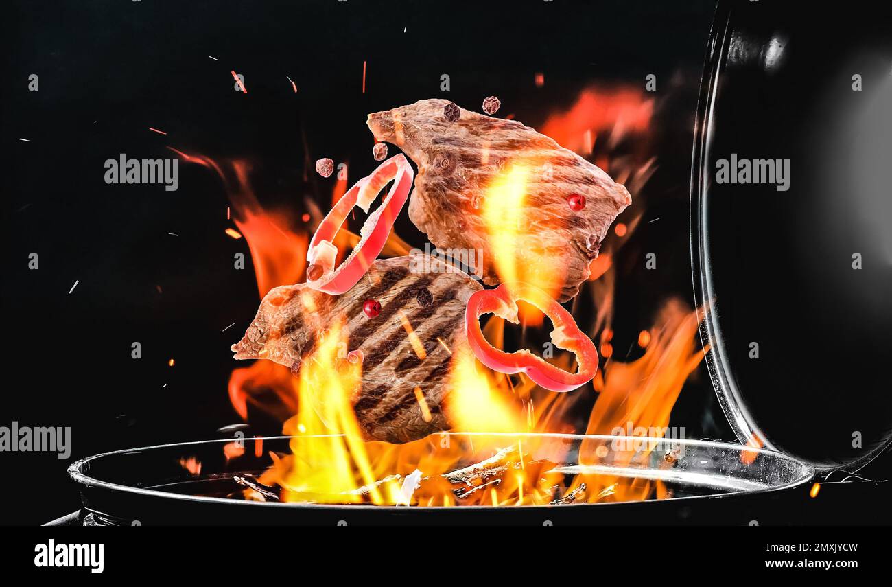 Meat and bell pepper slices falling onto barbecue grill with flame ...