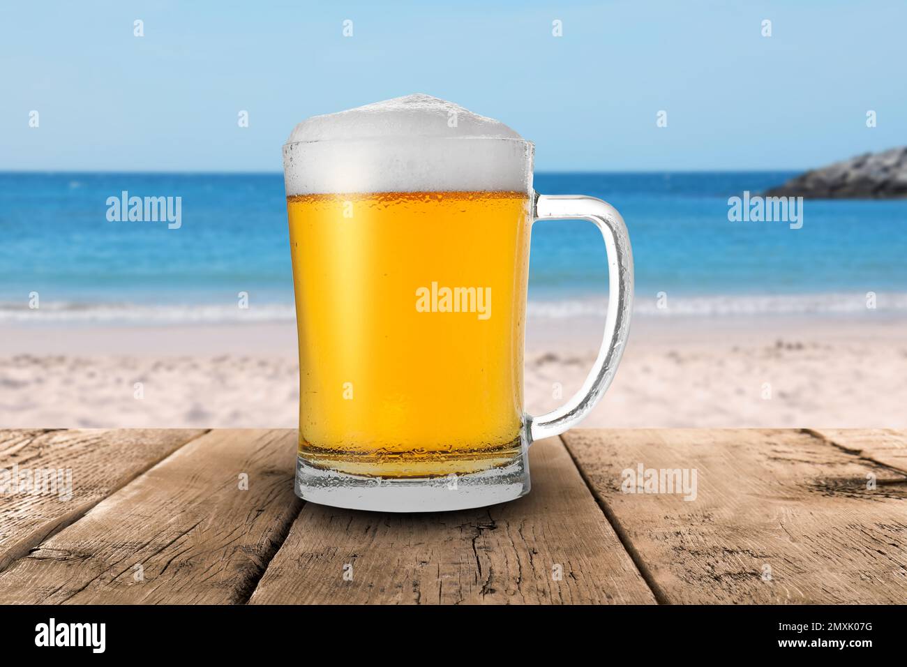 Cold beer on wooden desk against blurred sea and sandy beach Stock ...