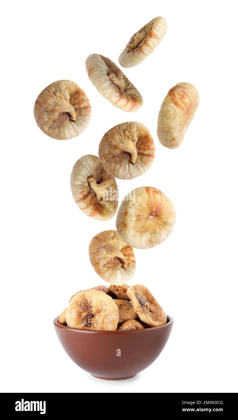 Dried fig fruits falling into bowl on white background Stock Photo - Alamy