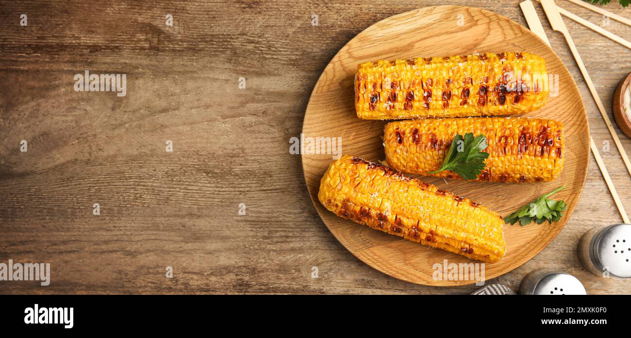 Delicious grilled corn cobs and space for text on wooden table, flat ...