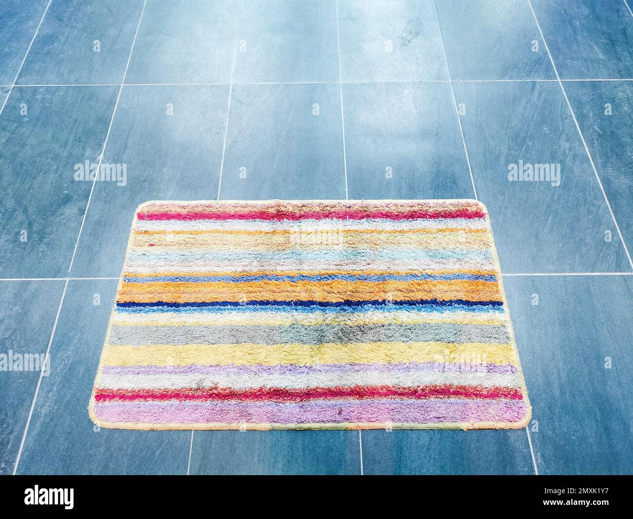 Colorful floor mate on the grey tiles. Selective focus Stock Photo - Alamy