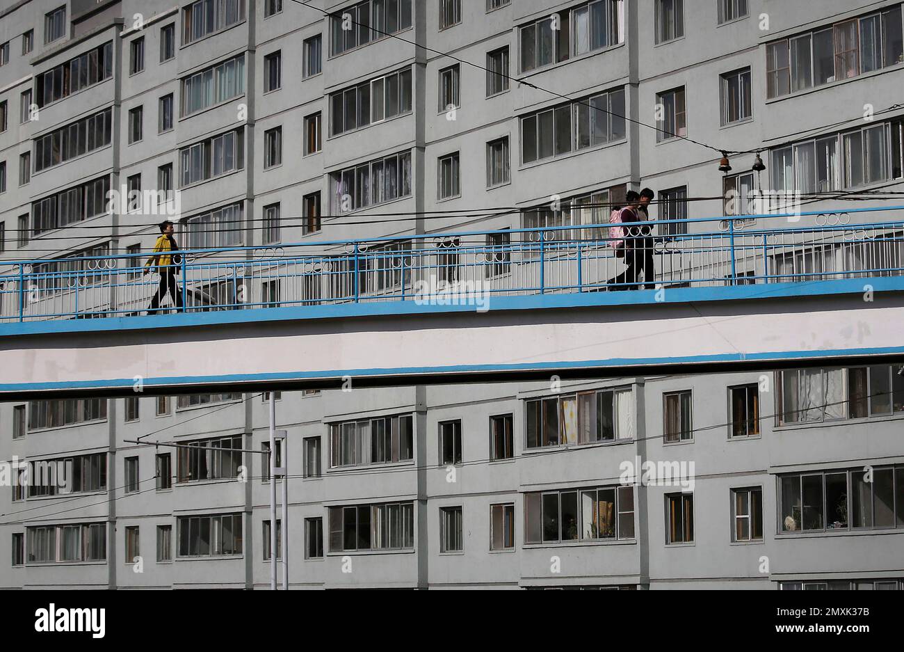 North Koreans walk past a residential building as they use an overhead ...