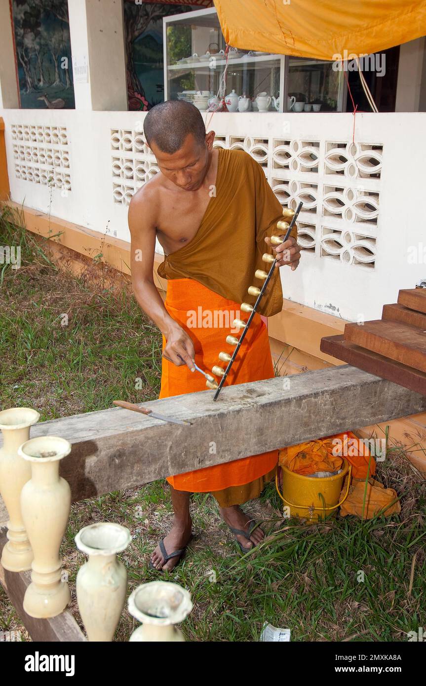 Buddhist monk cleans golden bells in Buddhist monastery, Koh Lanta ...
