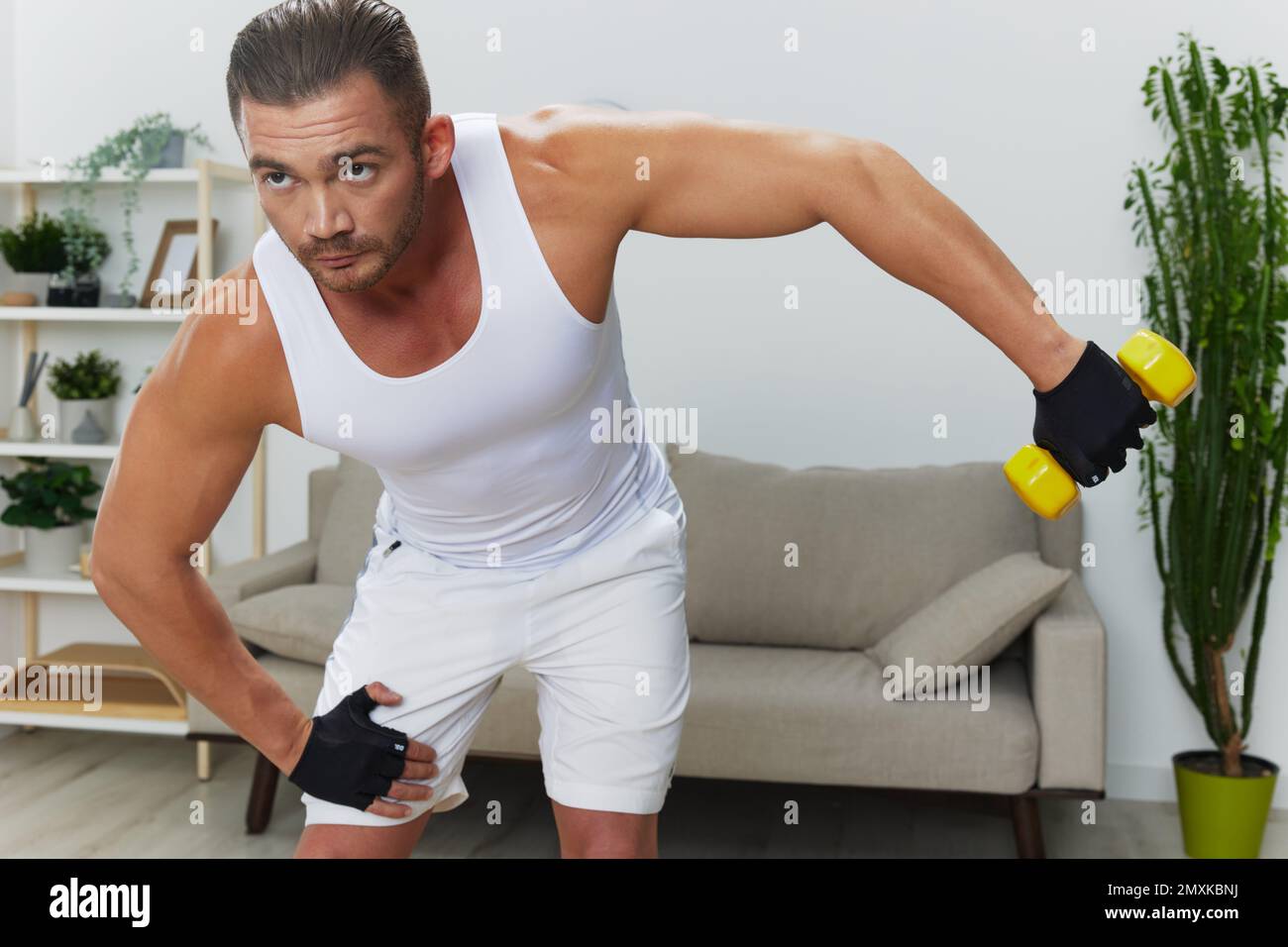 Man sports home training on the floor on a mat with dumbbells ...