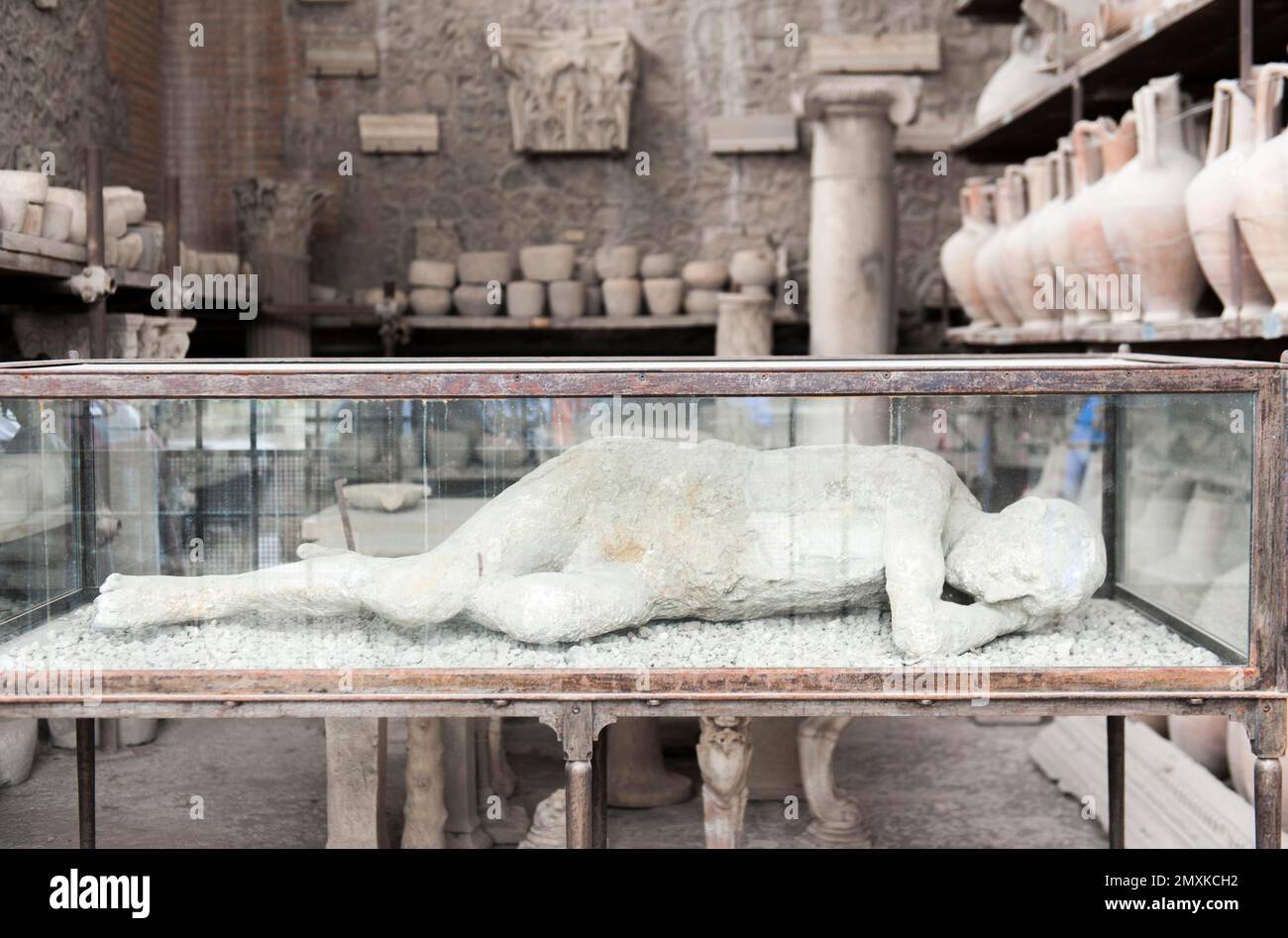 Archaeology, plaster cast of a reclining human in glass case in front ...