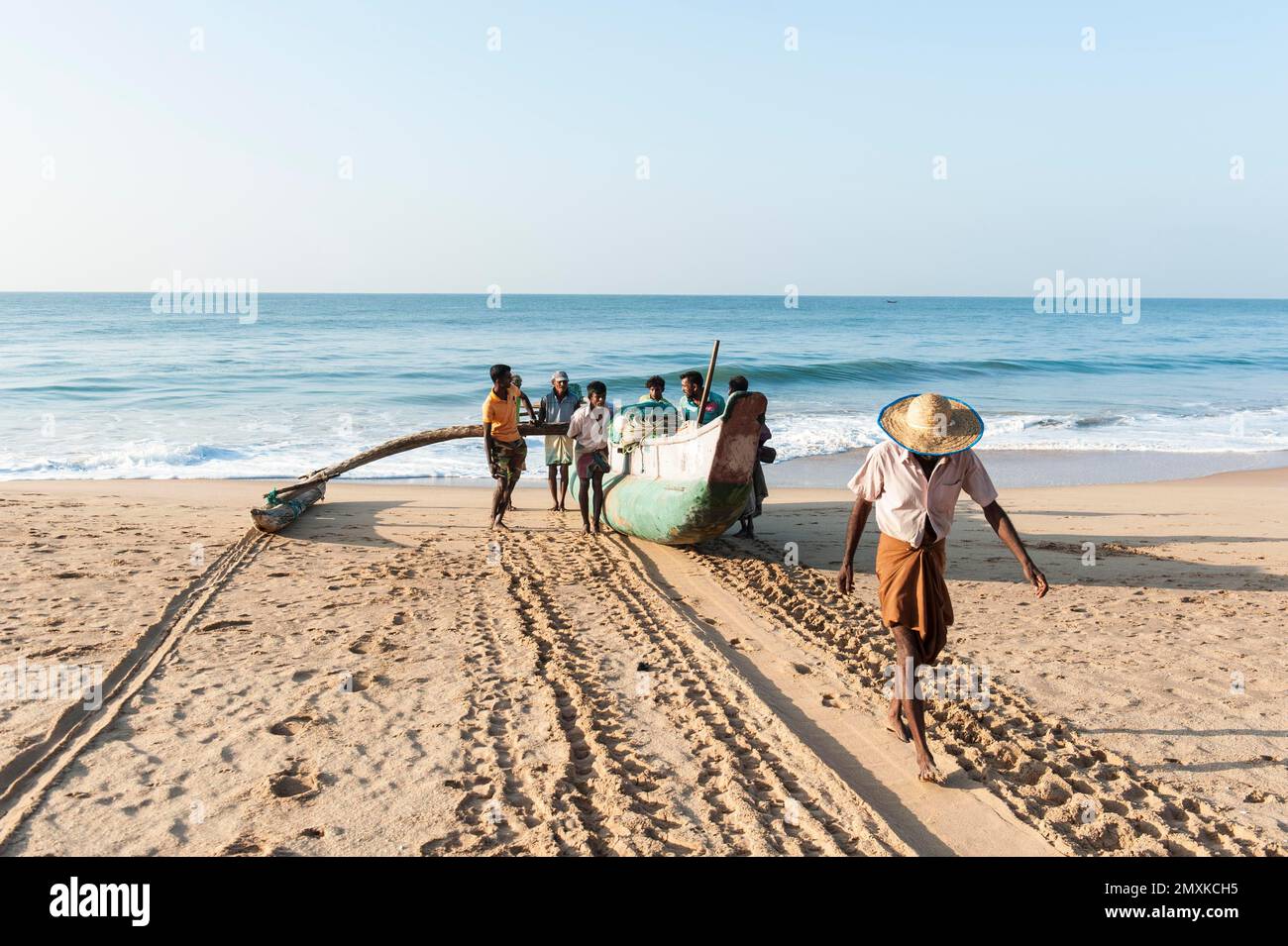 Fishermen pull fishing boat out of the sea onto the sandy beach, dugout ...