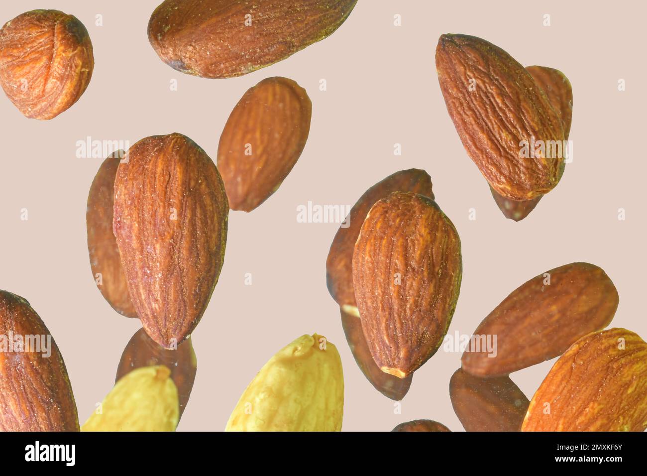 Flying in air fresh raw whole almonds isolated on a pastel background ...