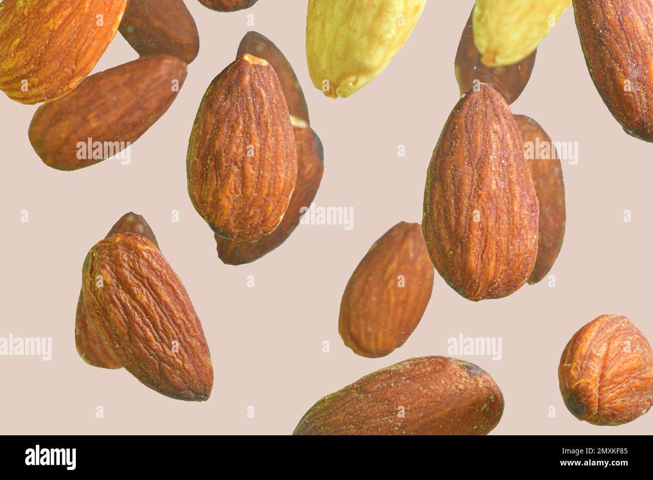 Flying in air fresh raw whole almonds isolated on a pastel background ...