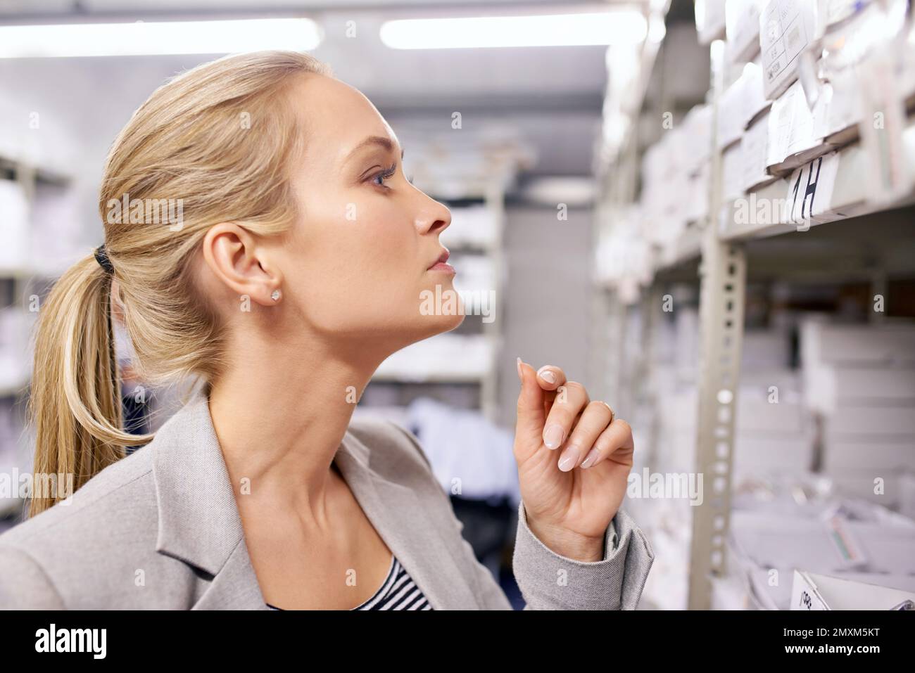 Finding the special order. a woman searching shelves in a distribution ...
