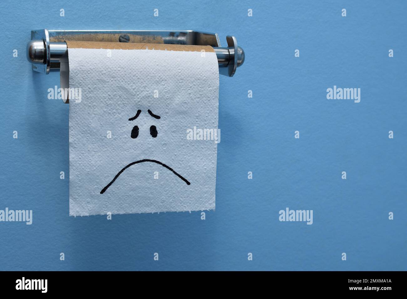 A close-up of a sad face on the last piece of toilet paper/tissue on a ...