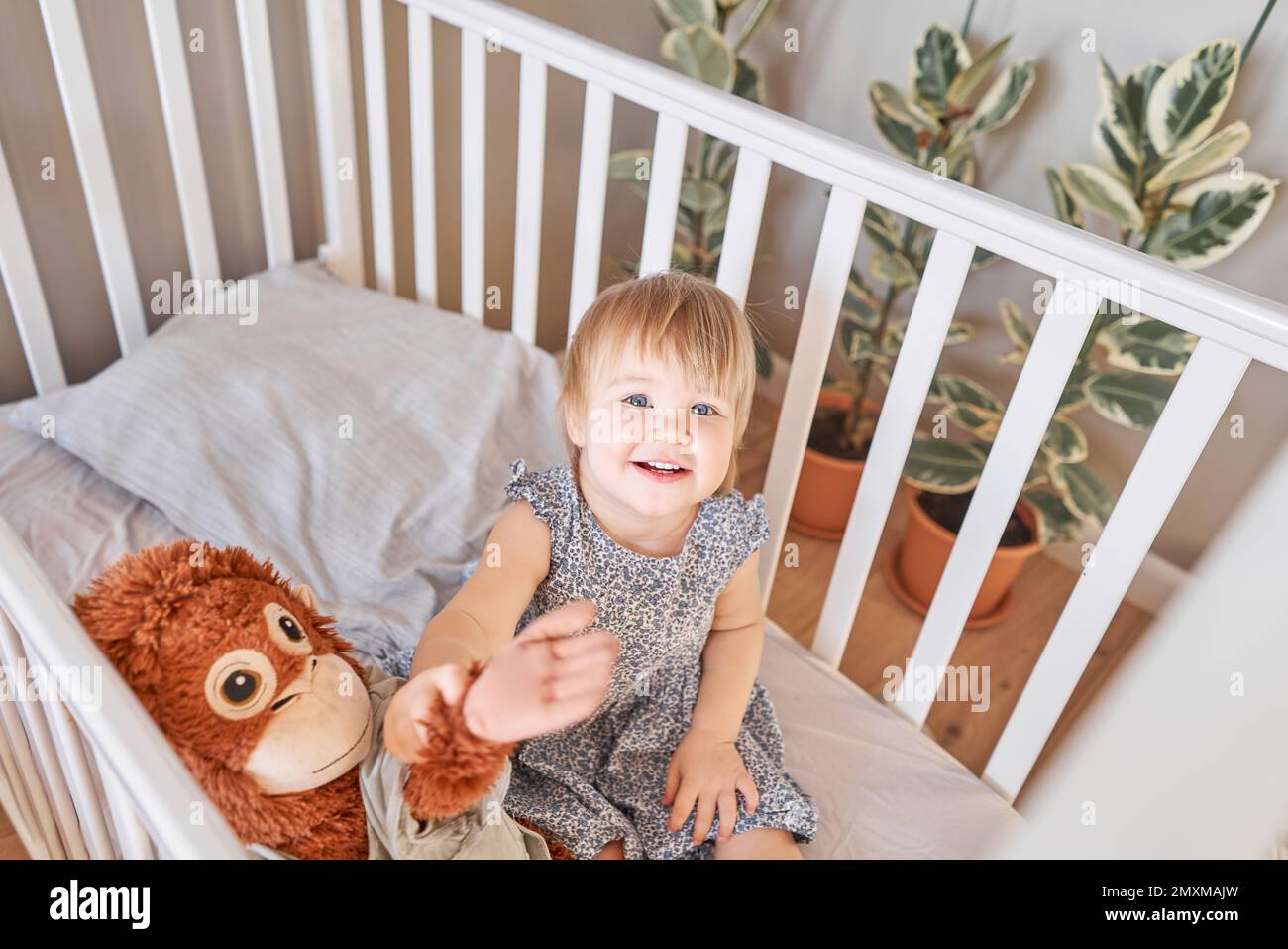 Happy baby girl one and half standing in the crib. Smiling 18 months ...