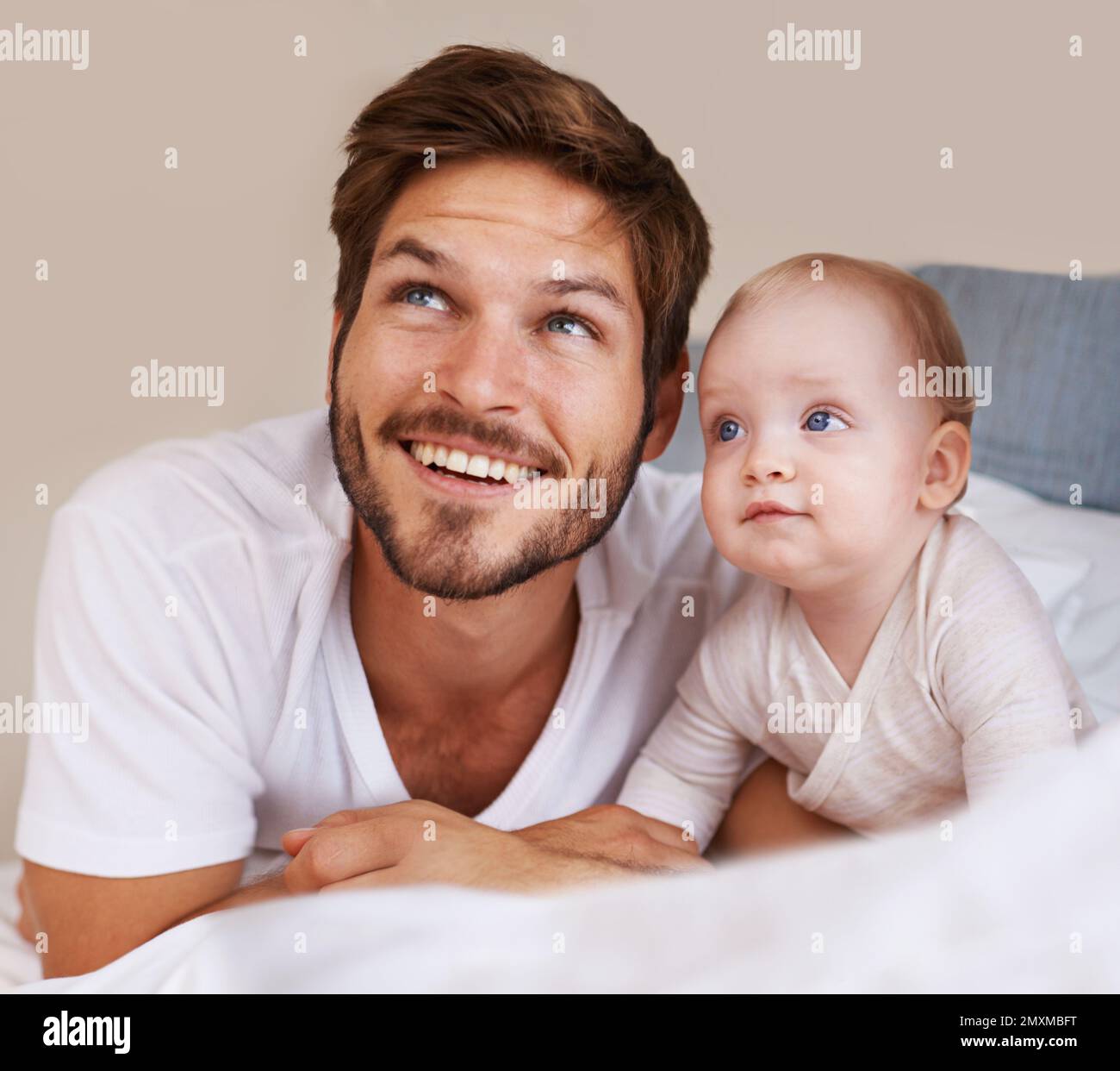 Watch the birdy. a young father and his infant son lying on a bed Stock ...