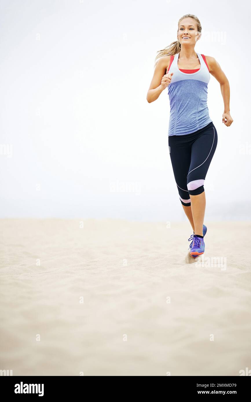 Getting fitter with every stride. a young woman jogging on the beach ...