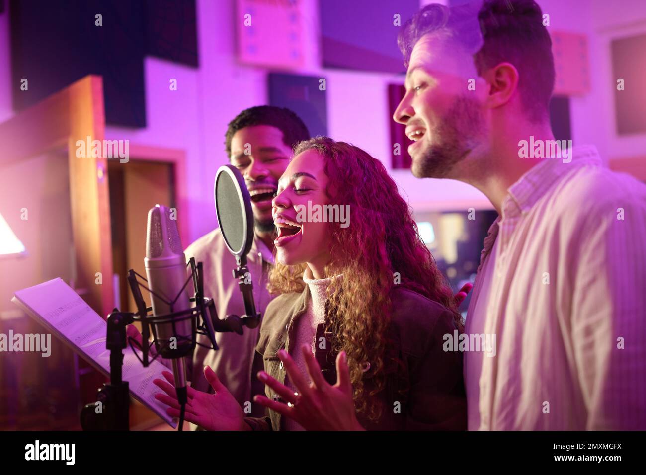 Woman, face or singing group on neon studio microphone in backup ...
